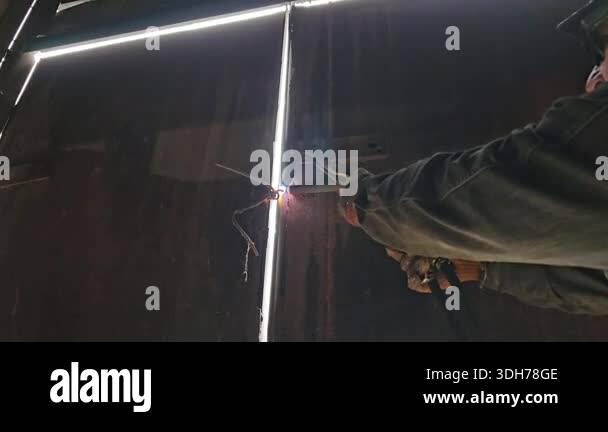 Slow motion footage of welder man welding metal beams in factory with ...