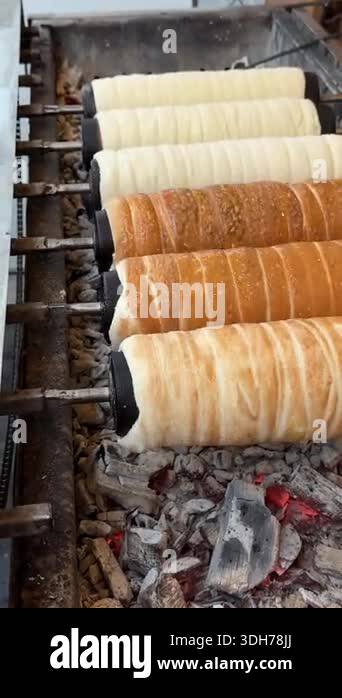 Spinning cylindrical trdelnik dough slowly browning on grill ...
