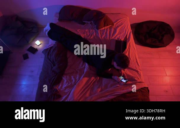 Lonely young man using smartphone in bed at night, isolated in dark ...
