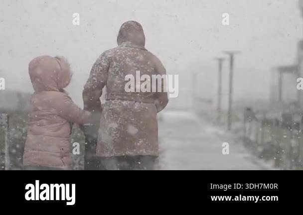 Family walks together in heavy snow during a snowstorm outside Stock ...