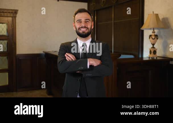 Smiling receptionist in a formal suit crossing arms in lobby. A ...