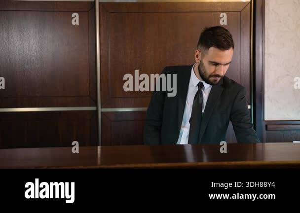 Young professional male concierge working at the hotel reception desk ...