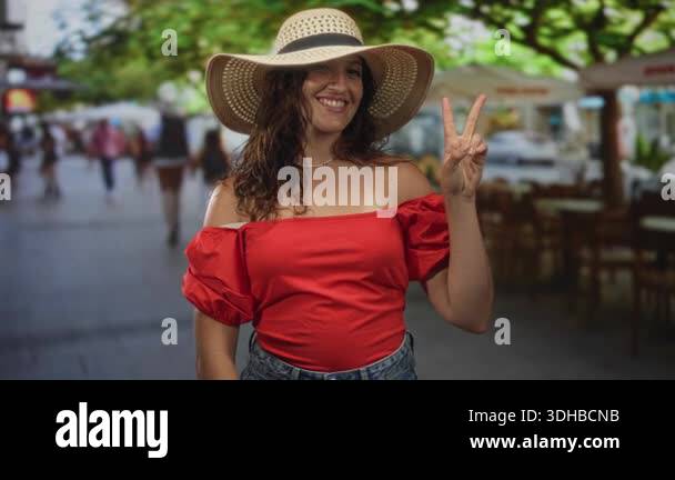 Woman showing peace sign with raised hand on a street terrace ...