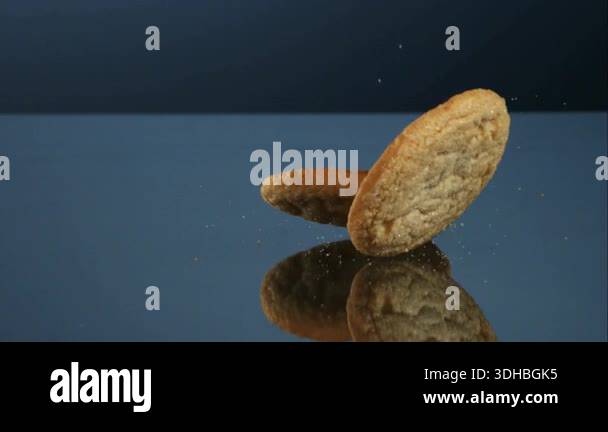 Soft round golden cookies falling and bouncing on a reflective gray ...