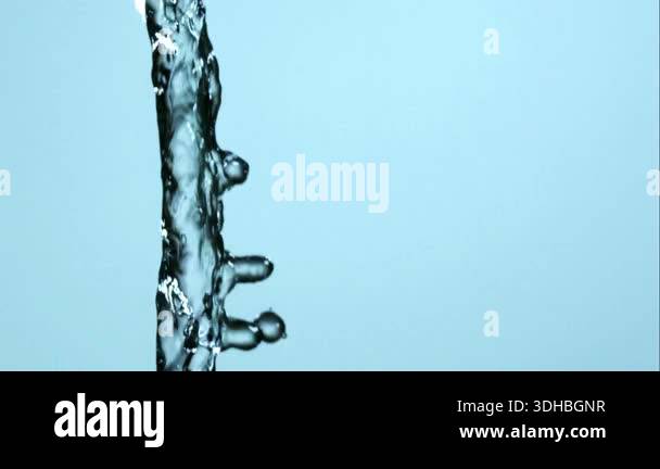 Clear liquid water stream pouring downwards in slow motion against a ...