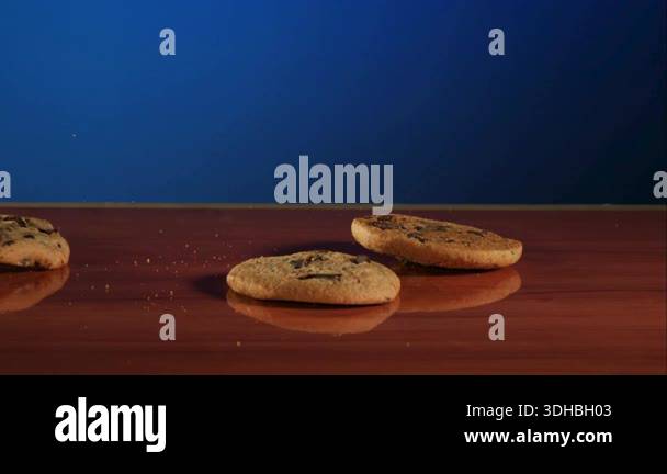 Several chocolate chip cookies falling and bouncing on a reflective ...