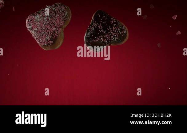 Heart shaped donuts with chocolate icing and pink sprinkles falling ...