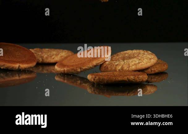 Assorted round cookies falling and bouncing on a dark reflective glass ...