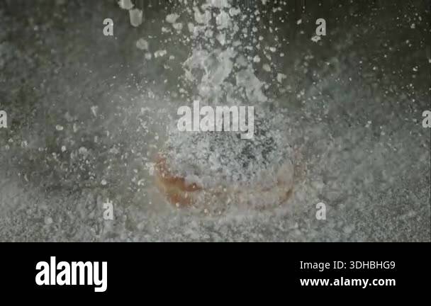 Delicious round donut covered in white powdered sugar falling and ...
