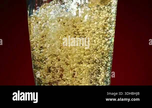 Close up of golden carbonated beer or soda being poured into a glass ...