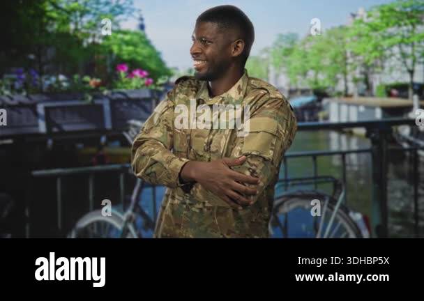 Soldier man in camouflage uniform smiling, arms crossed and giving a ...