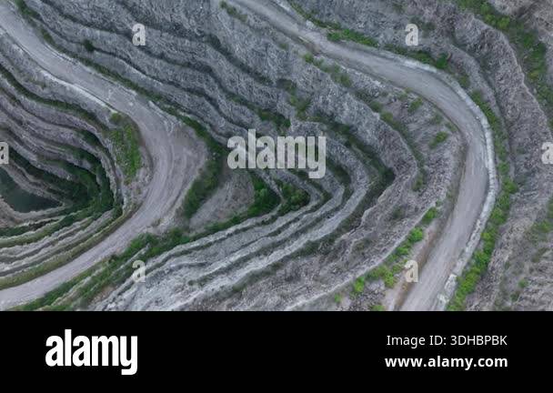 Excavation route turning tightly along terraced quarry slopes with ...