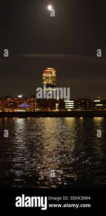 Bright moon over a modern city tower with shimmering reflections on the ...