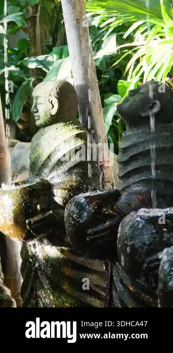 Sunlight illuminating a tranquil water feature with statues of buddhist ...