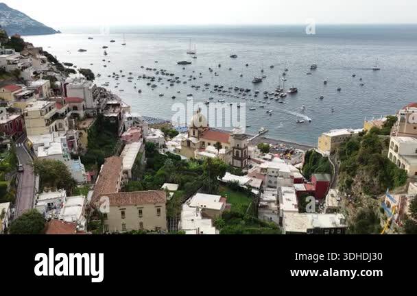 An aerial perspective of Positano. Buildings line the coast with boats ...