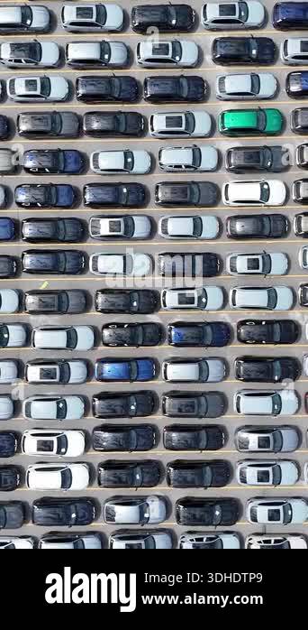 Overhead drone footage of many vehicles neatly parked in a crowded car ...
