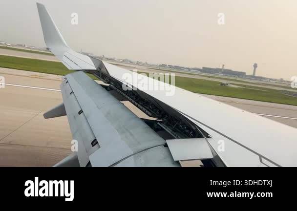 Airplane wing with flaps and spoilers deploying on the airport runway ...