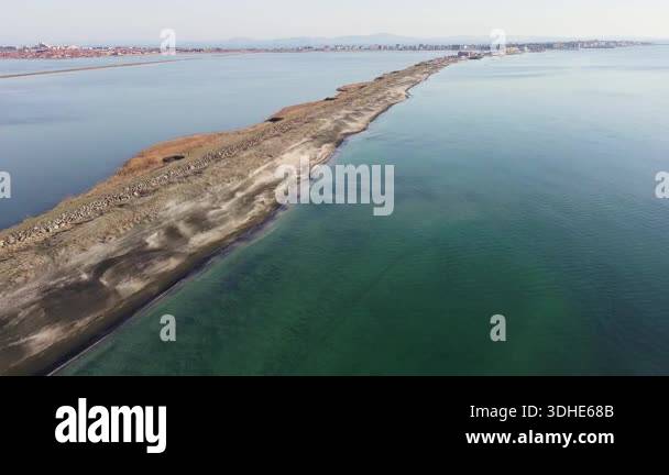 Birds eye view of narrow empty quiet beach with dry sand right and ...