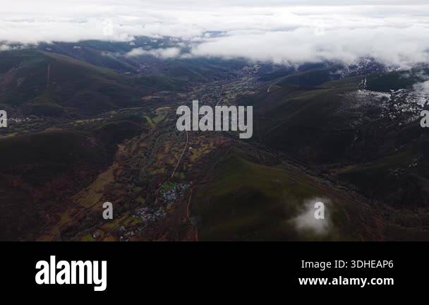 Aerial footage flying over a mountain valley with a small village ...