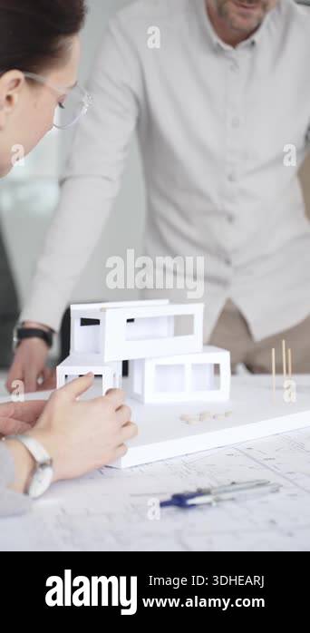 Architects discussing new building design, holding a compass over ...
