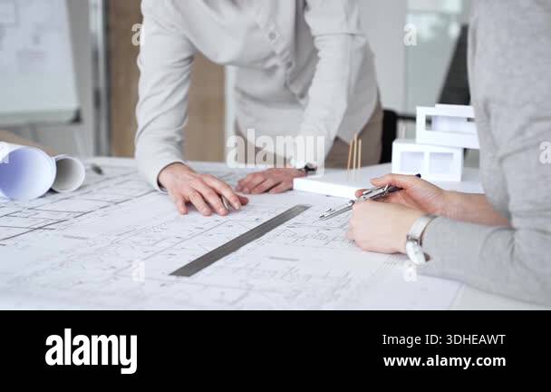 Architects discussing new building design, holding a compass over ...