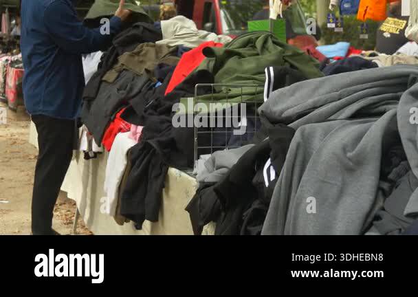Real-life scene of a man browsing clothes at a second hand stall ...