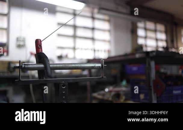 Metal pipe secured by a black C-clamp on a workbench in a workshop ...