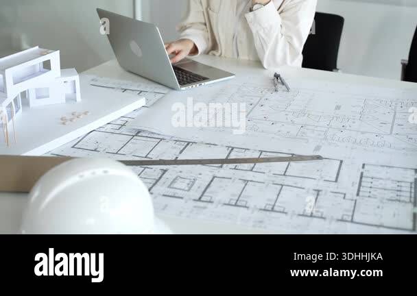 Architect analyzing blueprints alongside a physical building model ...