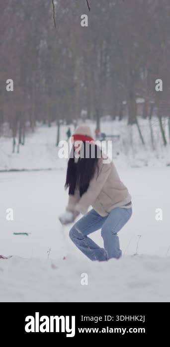 Smiling girl in warm jacket shoveling snow in winter park during ...