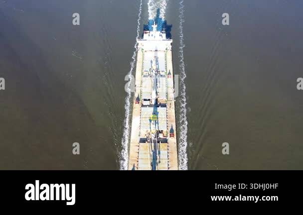 A massive cargo ship steams steadily out of the harbor, its hull ...