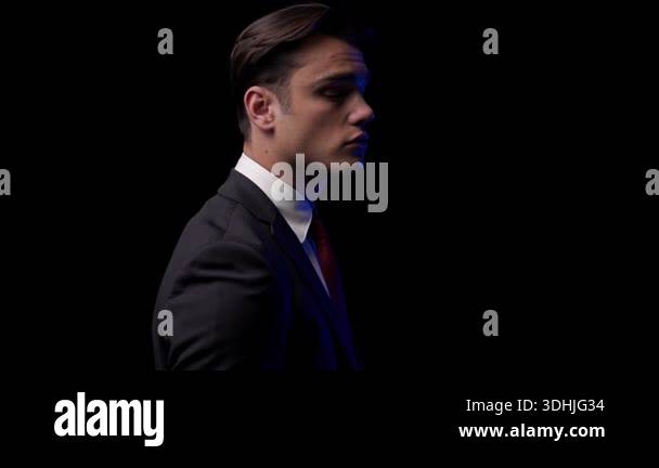 Side view of elegant man turning to camera, adjusting suit jacket with ...