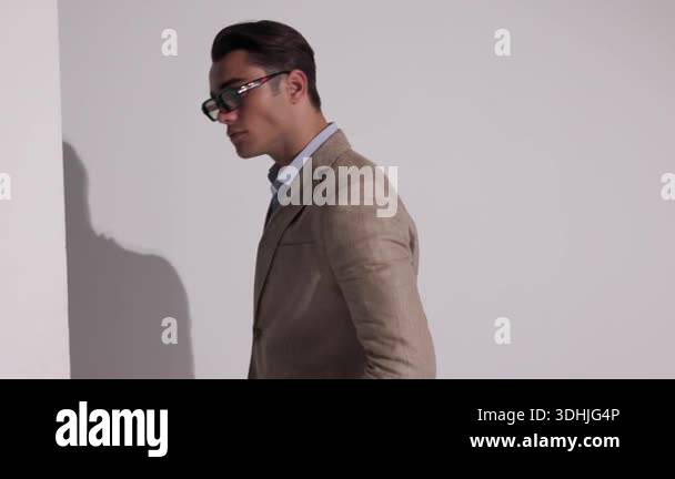 Stylish man in beige suit and sunglasses turning to camera, grabbing ...