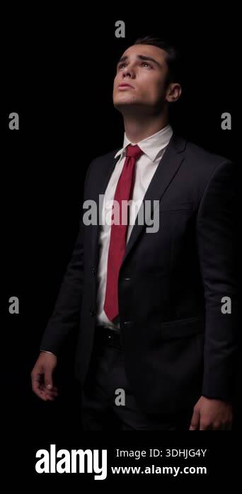 Fashion man looking up, buttoning suit jacket while turning to side and ...