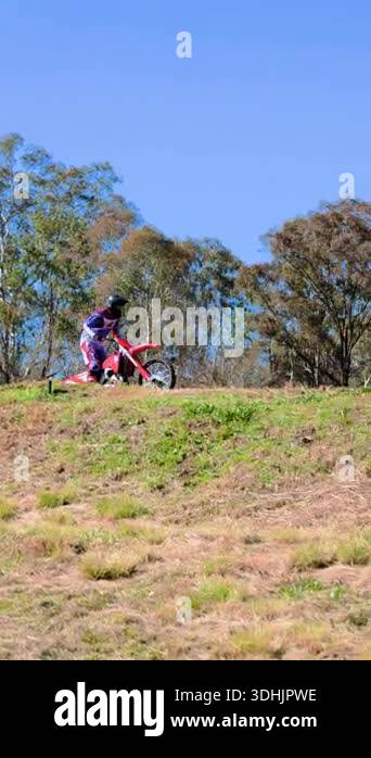 A motocross rider in full gear jumps and navigates a dirt track under ...