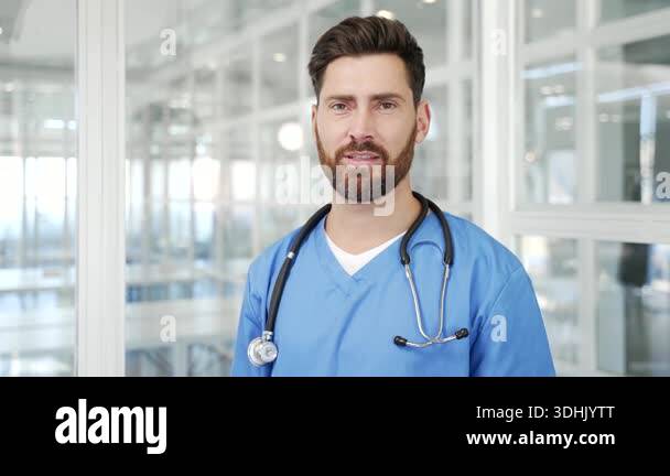 Portrait of smiling handsome doctor in blue coat standing in modern ...
