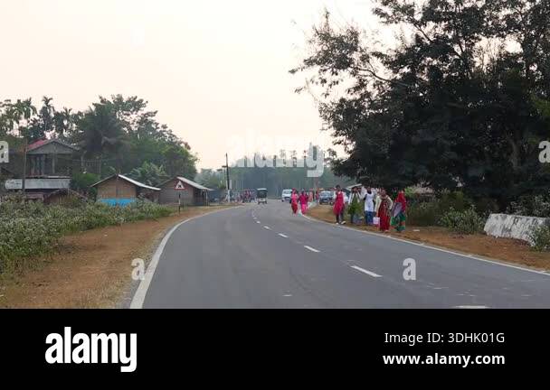 Assam, India January 2026: Villagers walking along a paved rural road ...