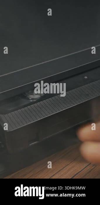 Male hand inserts black VHS cassette tape into motorized slot of ...