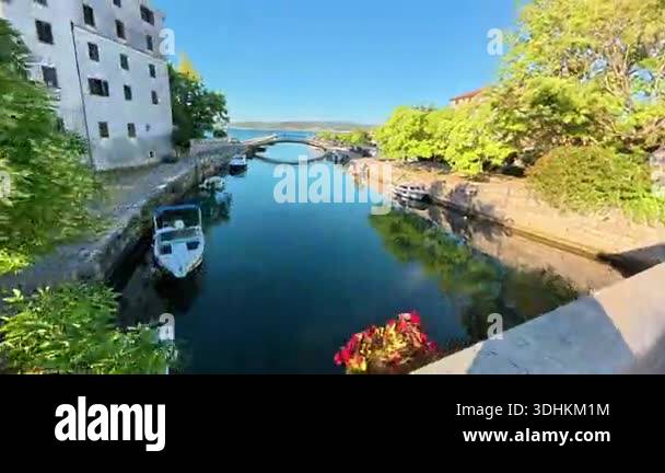 A narrow water canal with small boats moored along stone embankments in ...
