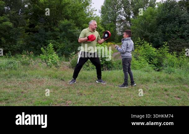 A boy strikes a pad under a coachs guidance, consistent punch practice ...