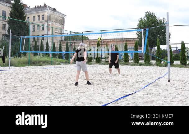 A man and a woman play beach volleyball on sand, a calm start of a long ...