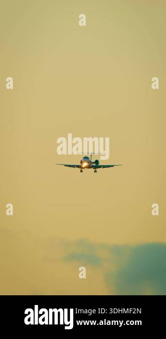 Airplane descending with headlights glowing and landing gear lowered ...