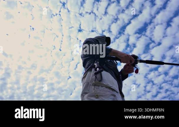 View up from below of an angler cast and reel casting rod and using ...