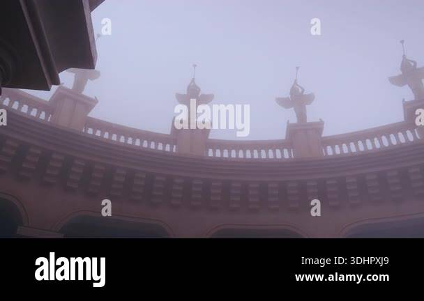 Upper Ring of stone Building with angel Statues emerging through dense ...