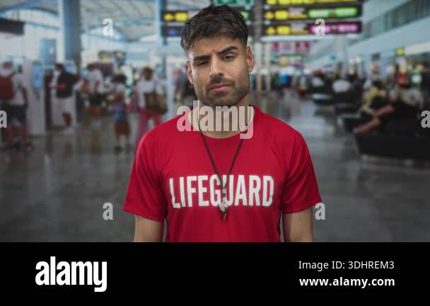Young hispanic man lifeguard standing in red shirt with whistle amid ...