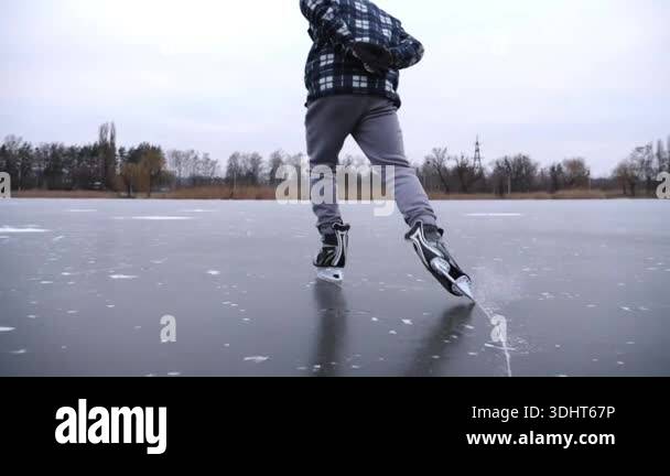 Guy skating on frozen river at cloudy day. Young man shod in figure ...