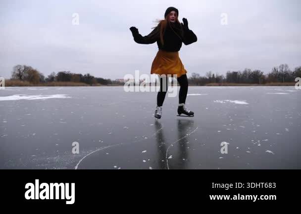Woman shod in figure skates sliding on ice rink at nature. Lady skating ...