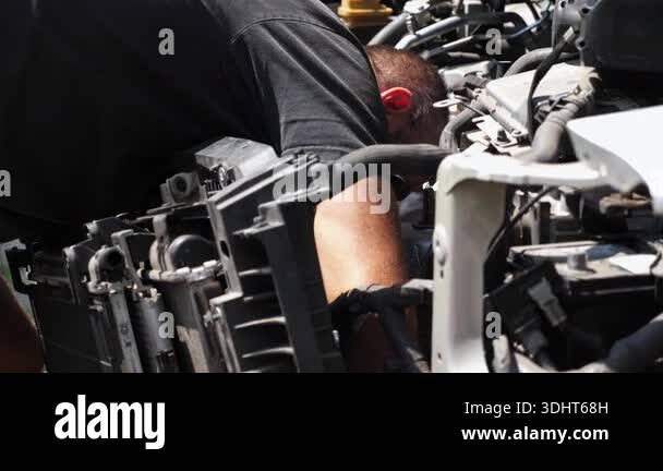 Professional repairman inspecting engine of a car at workplace. Male ...