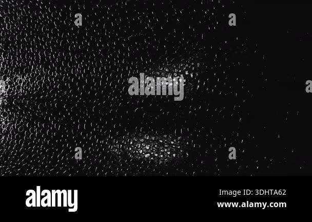 abstract rain droplets on black glass surface with soft light ...