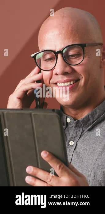 A cheerful man wearing glasses smiles while actively talking on his ...