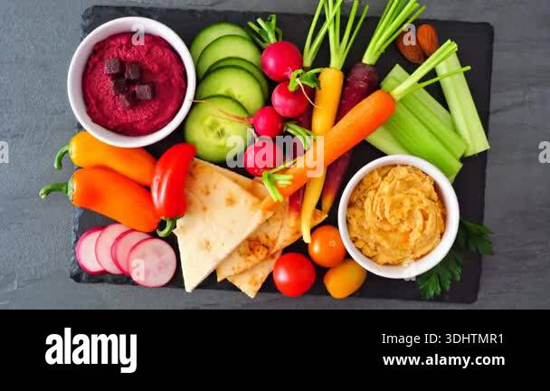 Variety of fresh vegetables and hummus dips on a serving platter. Slow ...
